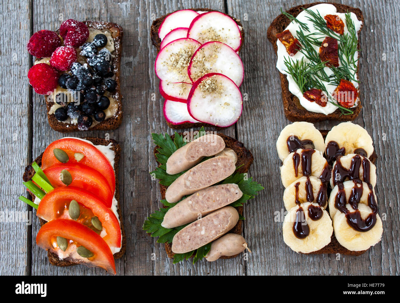 Top view of open sandwiches. Bread with nuts, bananas, berries, sausage ...