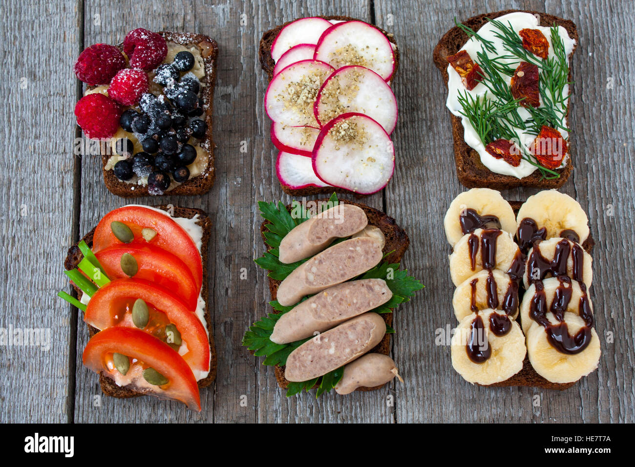 Top view of open sandwiches. Bread with nuts, bananas, berries, sausage ...