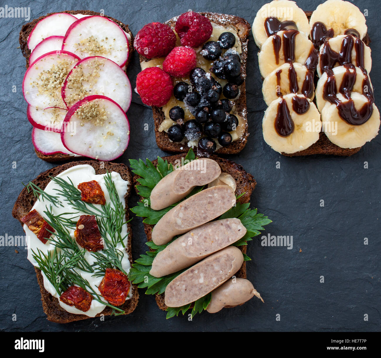 Top view of open sandwiches. Bread with nuts, bananas, berries, sausage ...