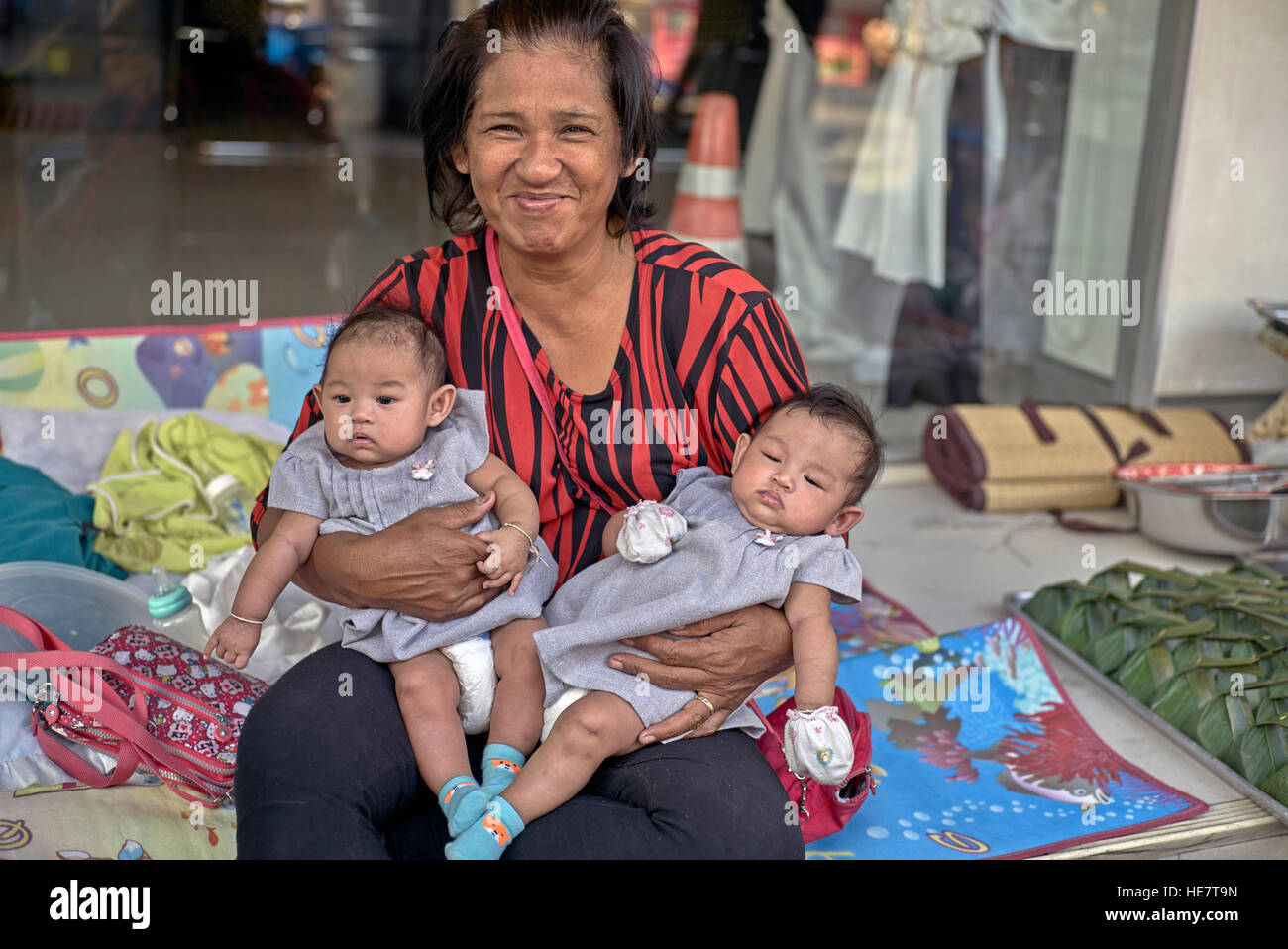 Grandmother and 3 month old identical twin baby sisters. Thailand S. E ...