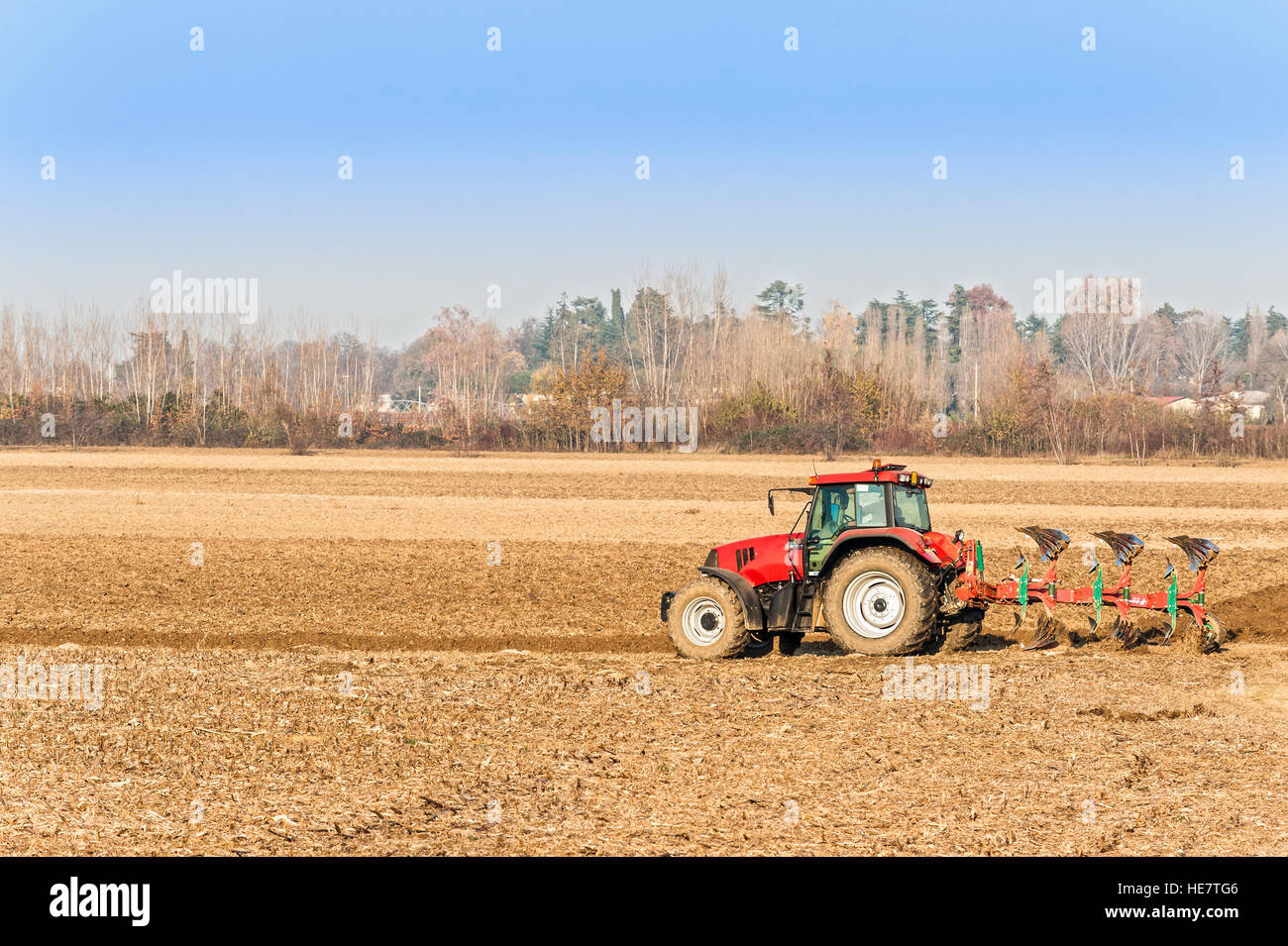 Agricultural labor, Red Tractor plowing a field Stock Photo - Alamy