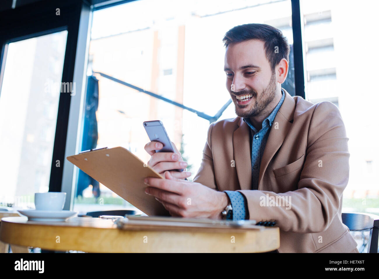 Businessman using phone in coffee shop Stock Photo - Alamy