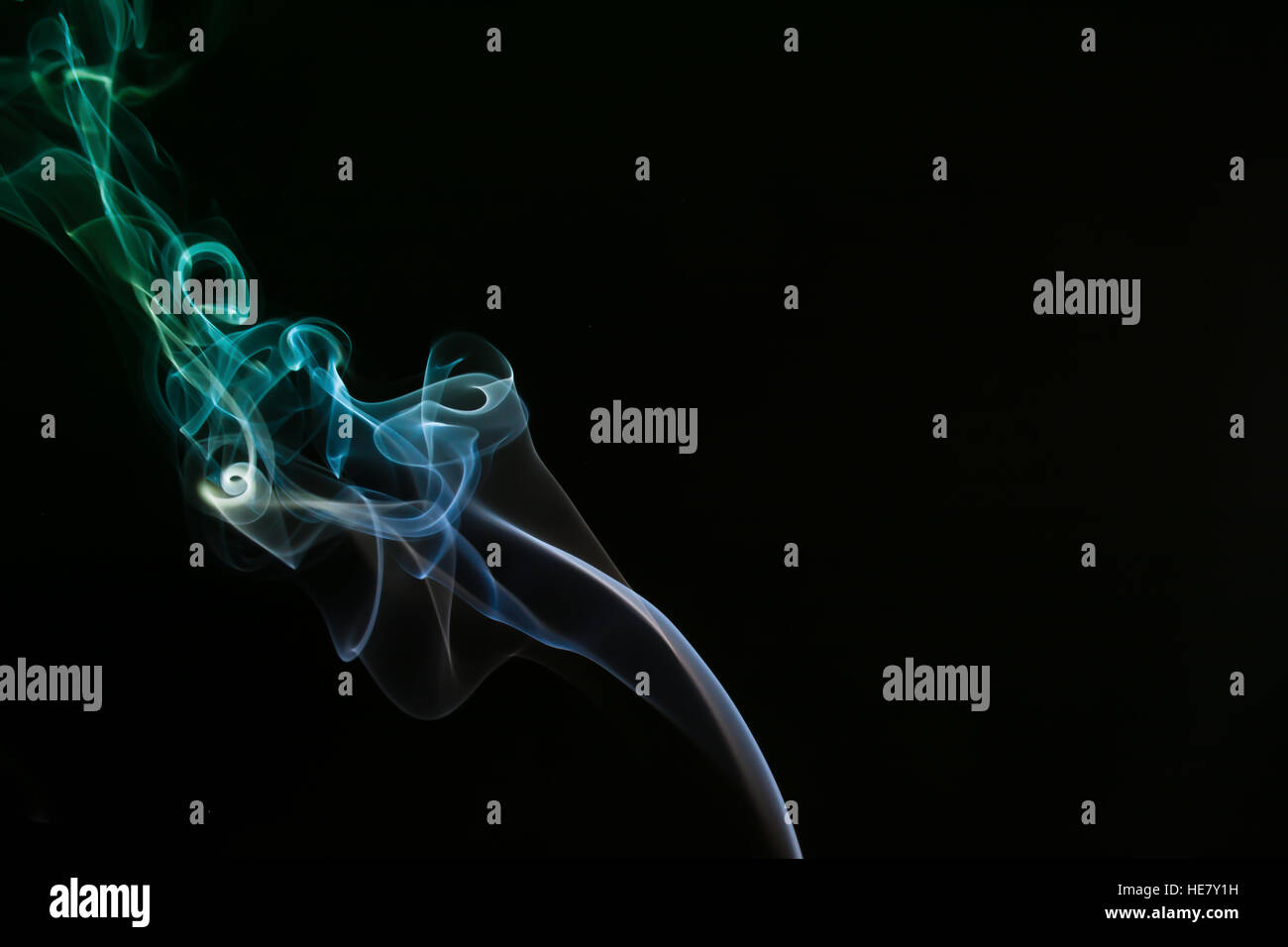 Blue green smoke trail on black background Stock Photo - Alamy