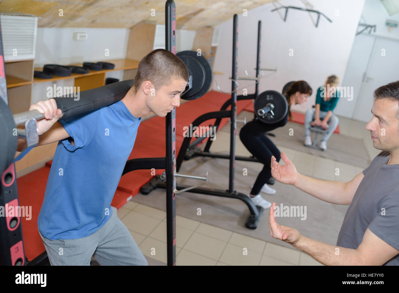 teen training with weights at gym club with coach Stock Photo - Alamy