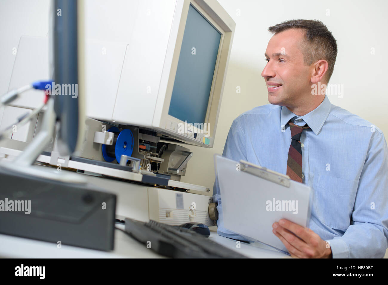 Man looking at computer monitor and smiling Stock Photo - Alamy