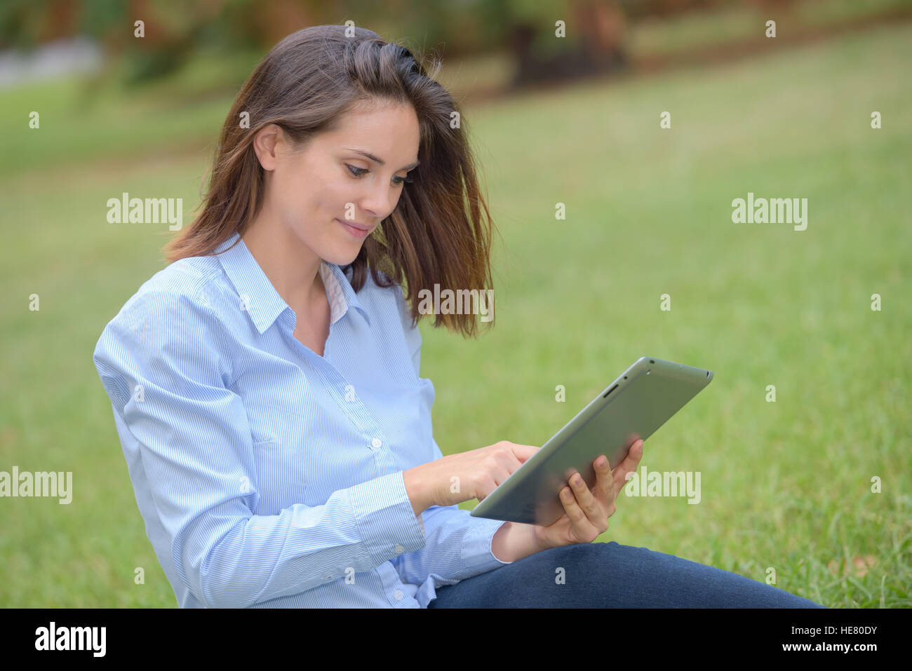 Woman sat in park using tablet Stock Photo - Alamy