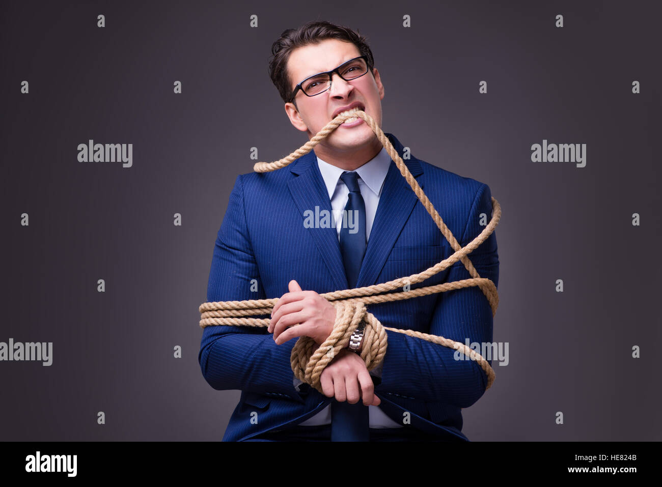 Businessman tied up with rope Stock Photo - Alamy