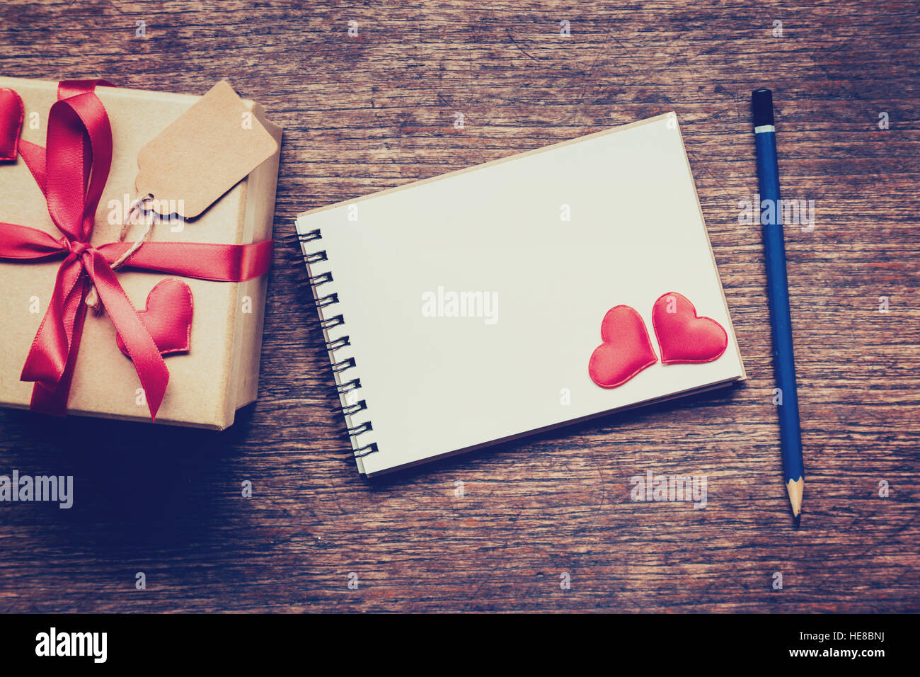 Top view (above) gift box and red ribbon and red heart with notebook on ...