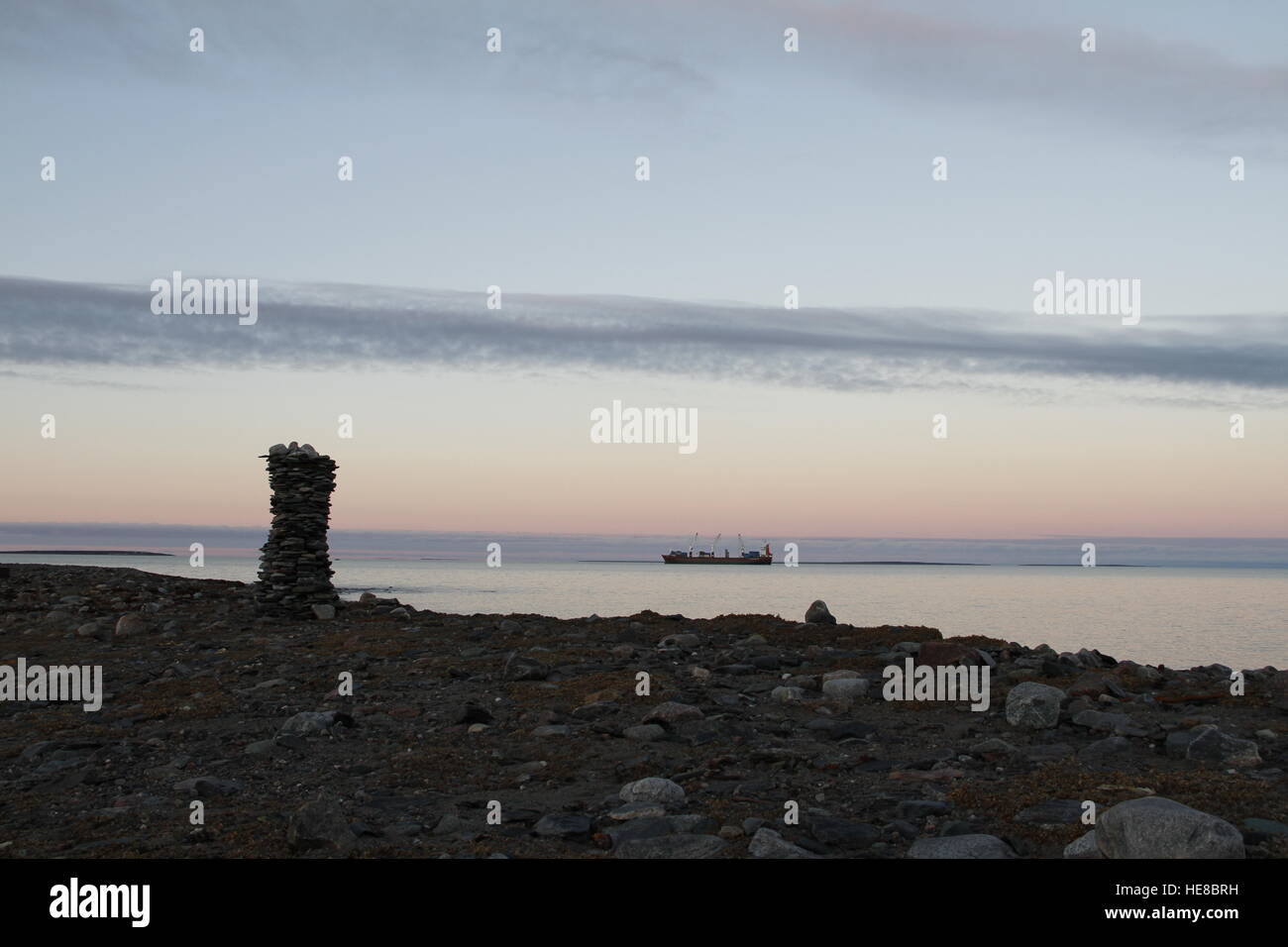 Inuksuk or Inukshuk along the Hudson Bay arctic shore with barge in ...