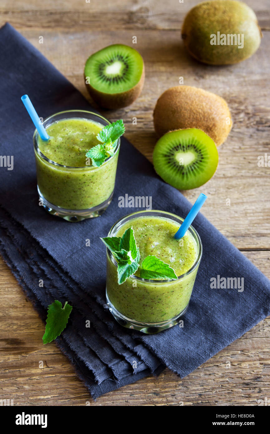 Green kiwi smoothie with mint leaves in glasses over rustic wooden ...