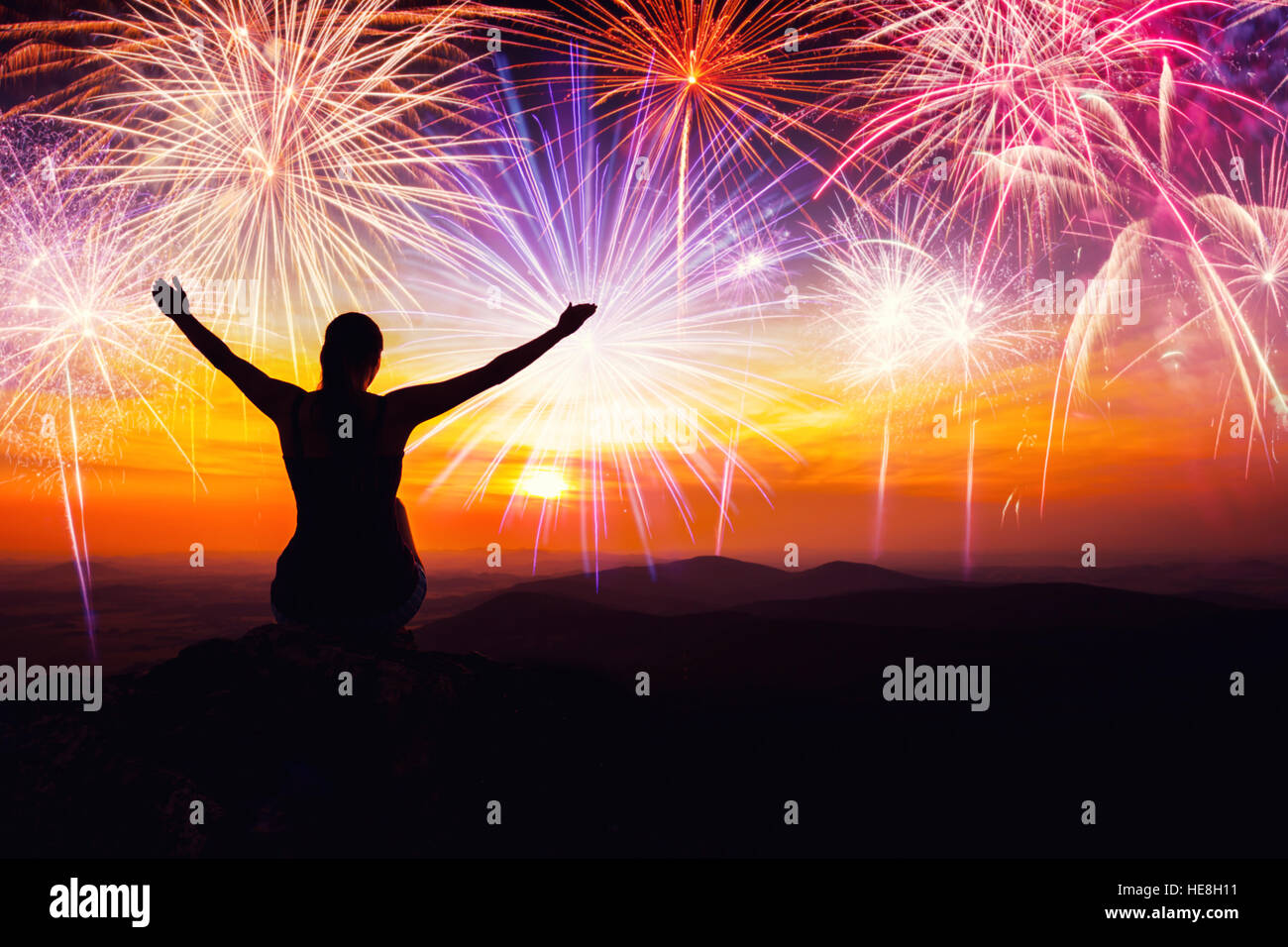 Silhouette of woman sitting, pointing and watching the fireworks ...