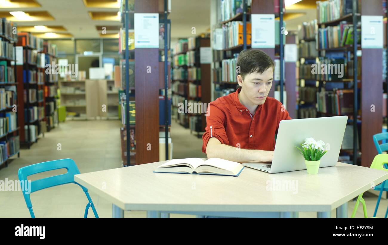 student boy sitting in library and using laptop Stock Photo - Alamy