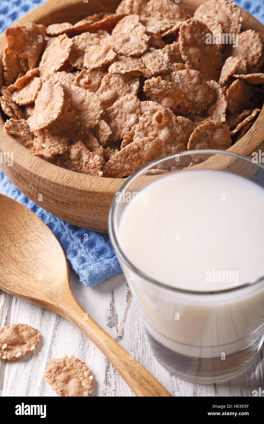Healthy bran flakes in a wooden bowl and milk close-up. vertical ...