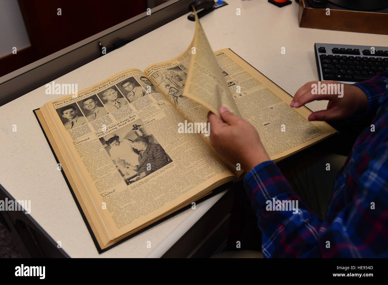 Christopher McCune, 460th Space Wing historian, turns a page in a book ...