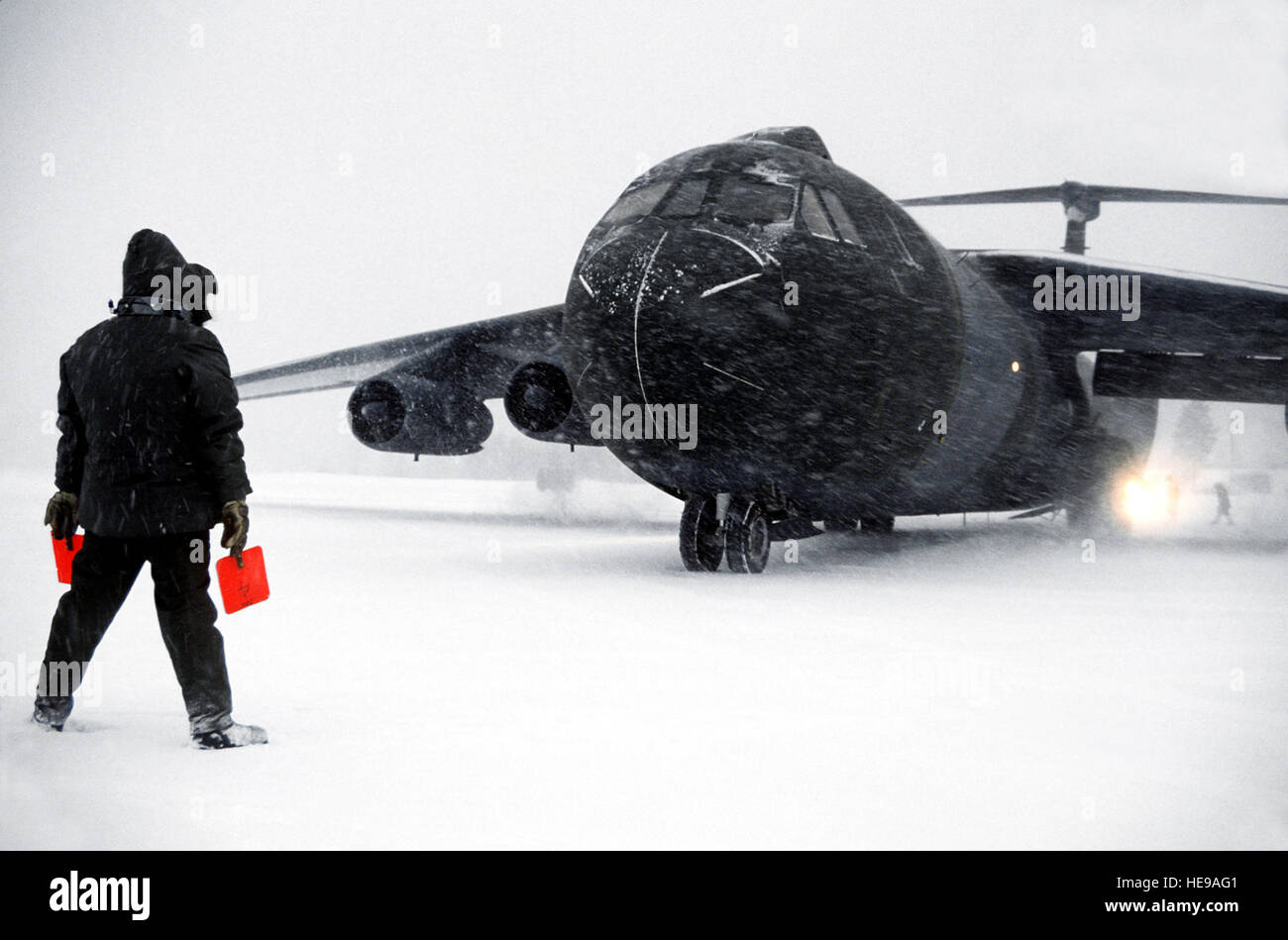 A flight line marshaler directs a camouflage-painted C-141B Starlifter ...