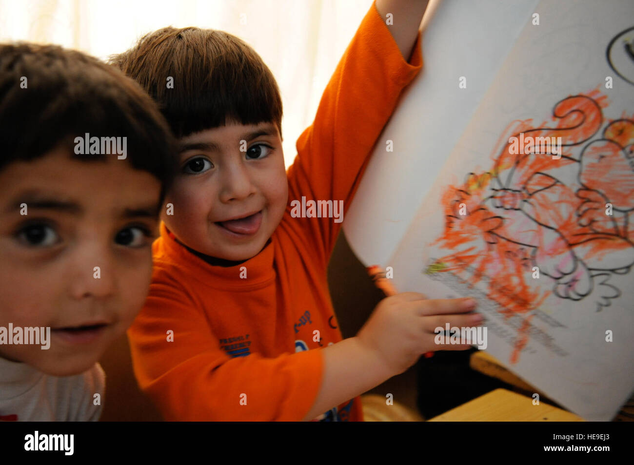 Two Afghan boys smile and show their drawings at a daycare within the ...
