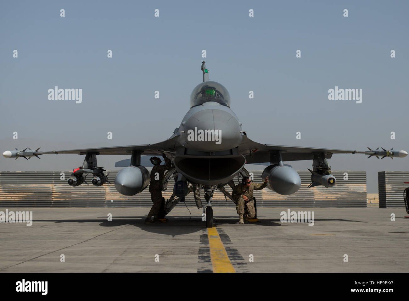 Air Force personnel conduct preflight checks on an F-16 Fighting Falcon ...