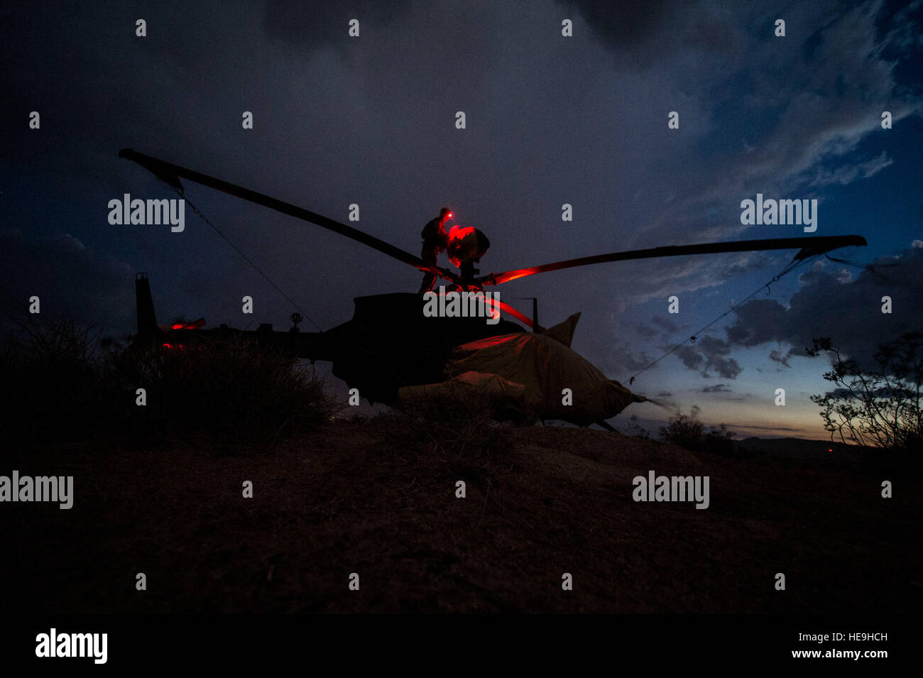 A U.S. Army OH-58D helicopter mechanic covers the helicopter's top ...