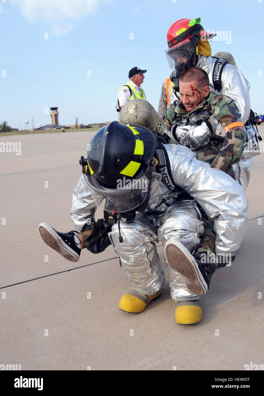 A role player with simulated injuries is evacuated by firefighters from ...