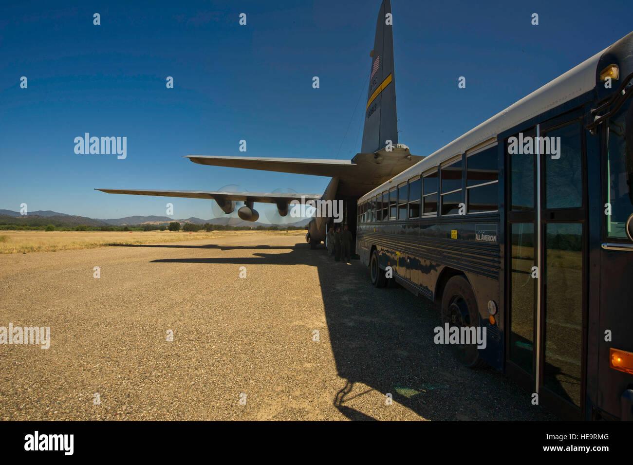 A Blue Bird ambulance bus backs up to a C-130 Hercules to offload ...