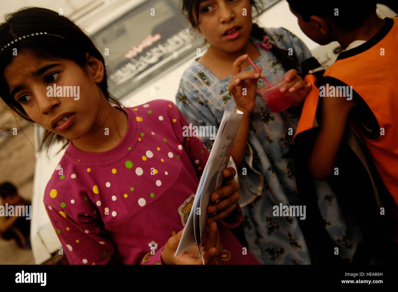 An Iraqi girl holds leaflets she received during a humanitarian aid ...