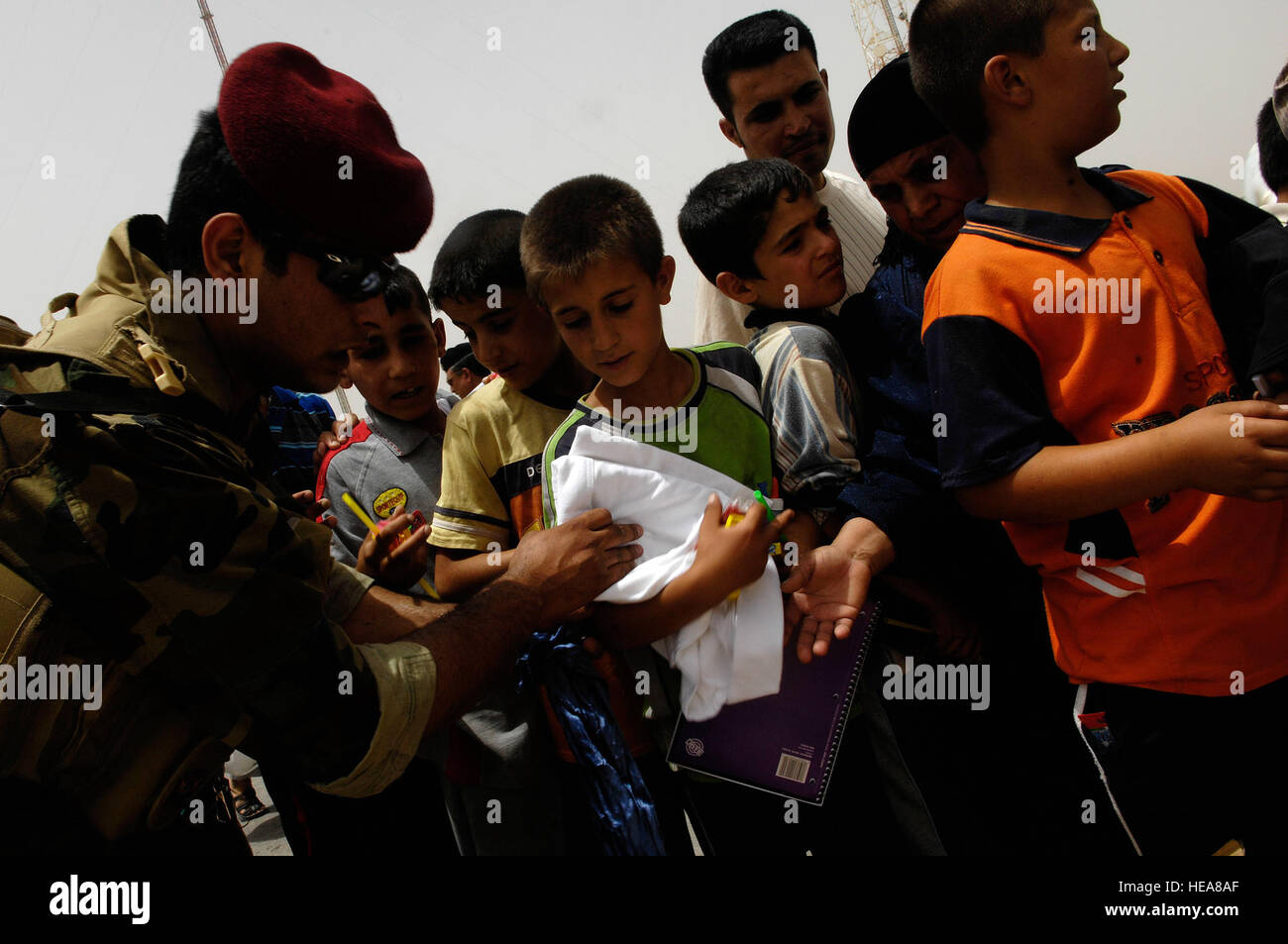 An Iraqi soldier distributes clothing to children during a joint ...