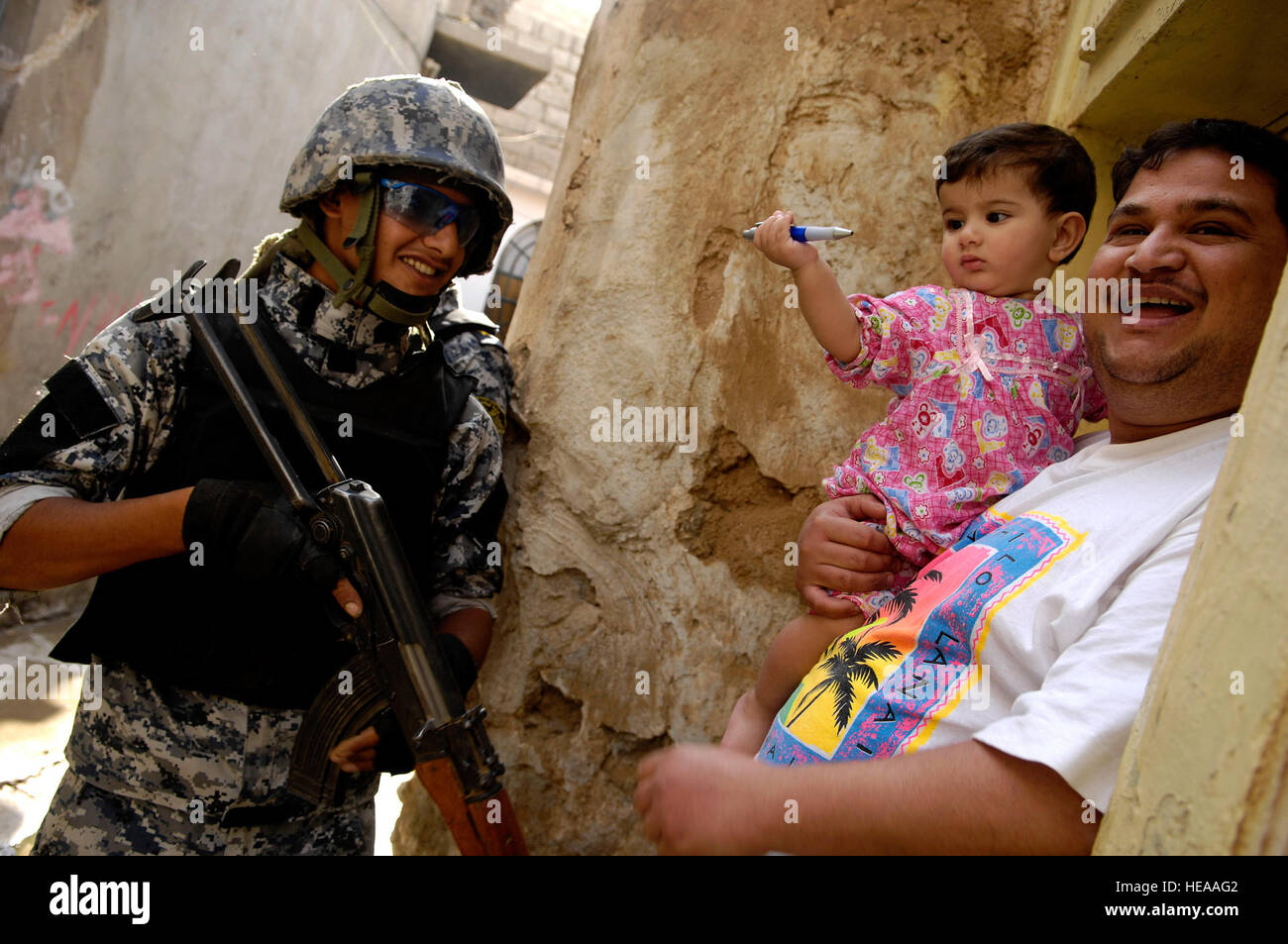 An Iraqi police officer greets an Iraqi man and his child during a ...