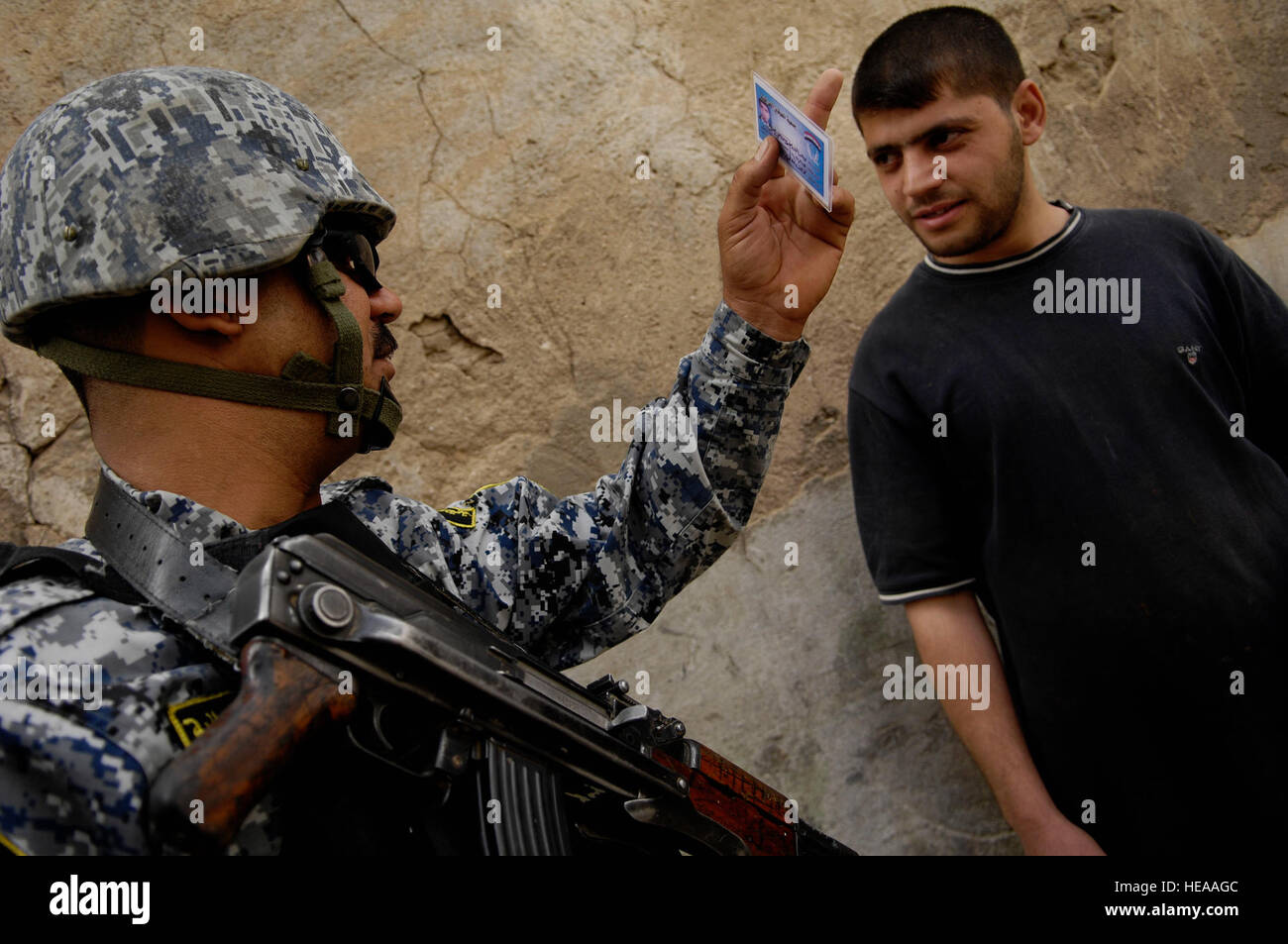 An Iraqi police officer checks the identification of an Iraqi man ...