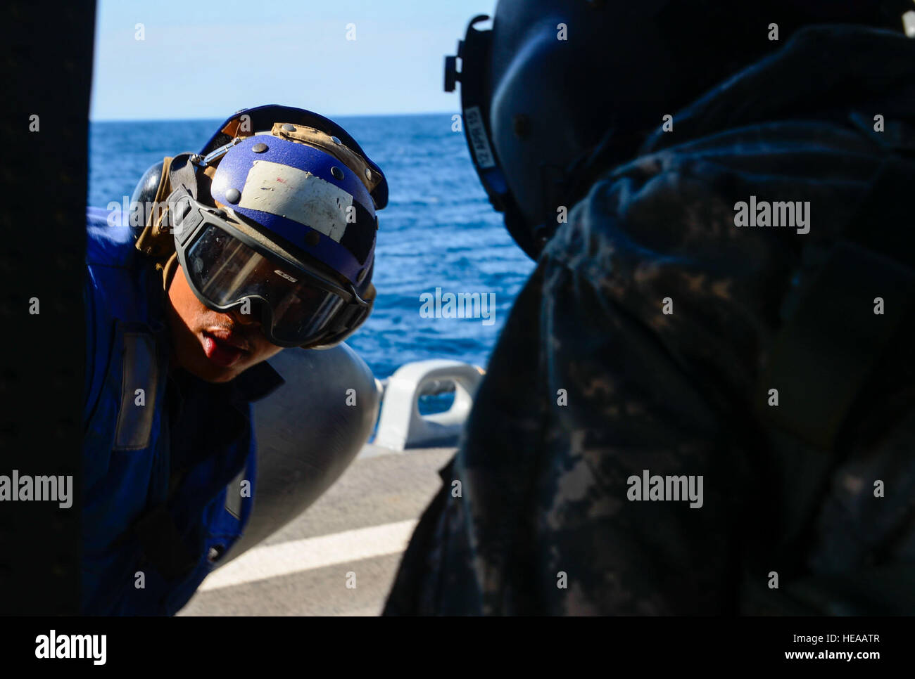 A U.S. Navy crew plane handler ties down a UH-60 Black Hawk helicopter ...