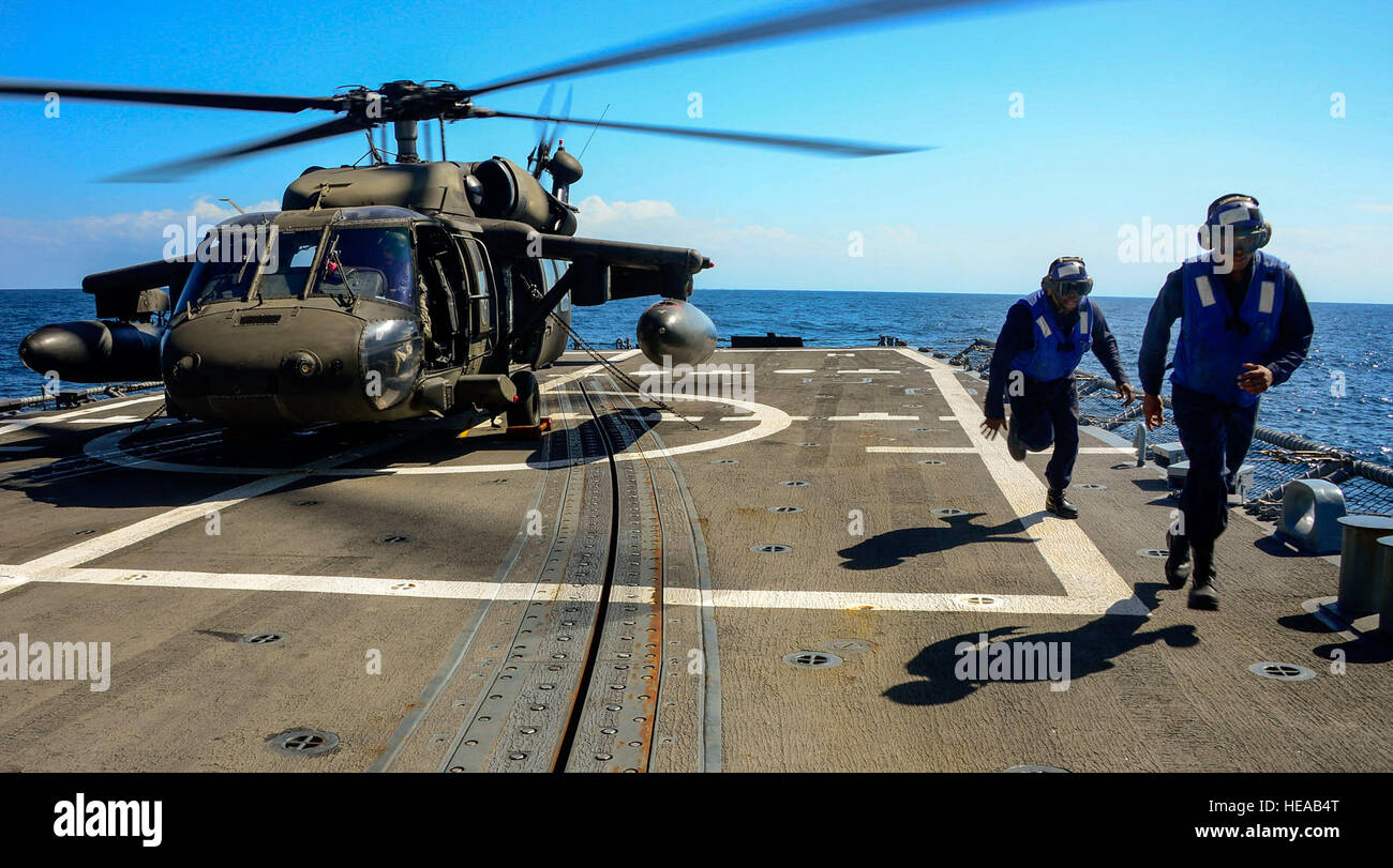 U.S. Navy plane handlers leave the rotor area after tying down a UH-60 ...