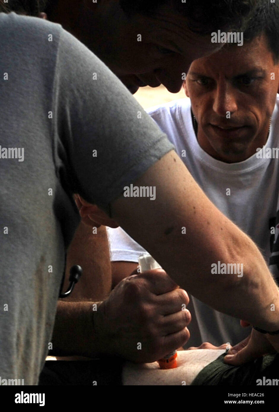 Army Sgt. 1st Class Robert Garnsey, center, administers an epinephrine ...