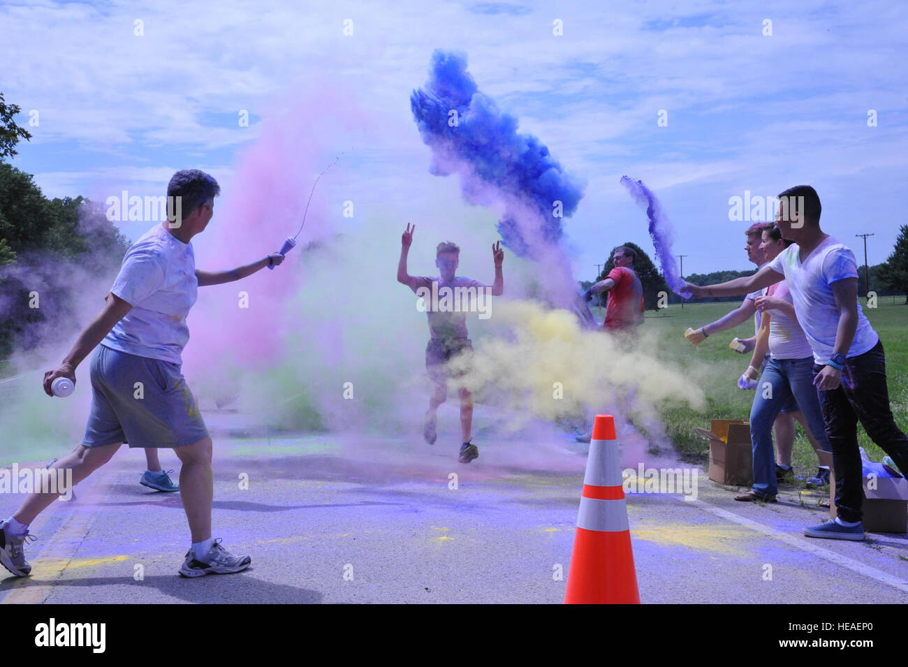 Volunteers douse a runner with color powder as he crosses the finish ...