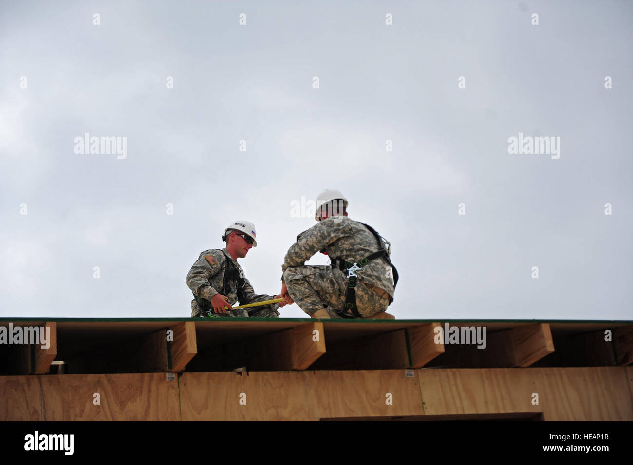 Two U.S. Army soldiers work on finishing the roof of a school house ...
