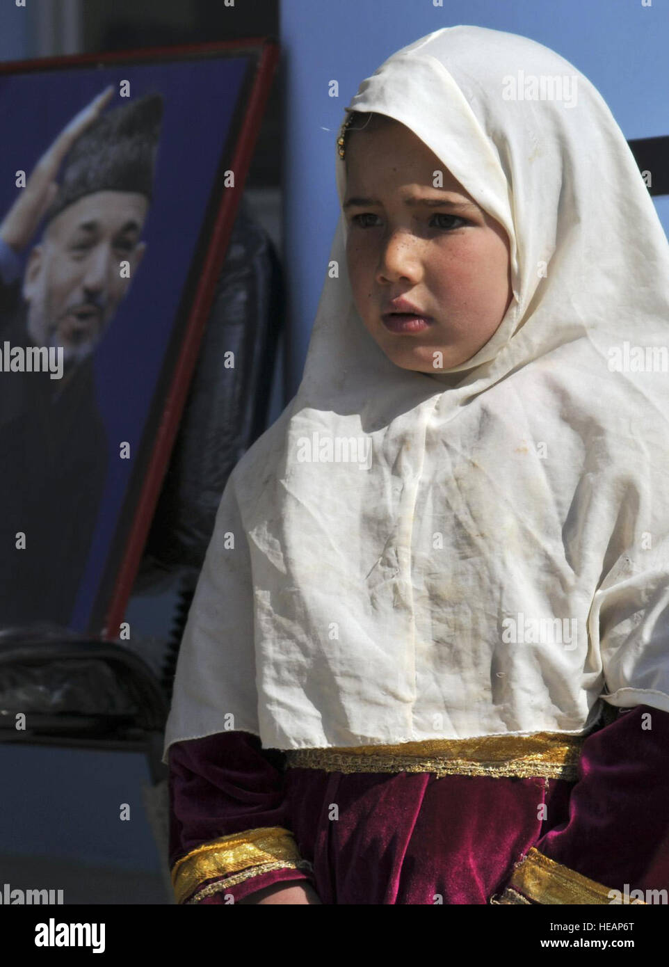 A young Afghan girl stands near a photo of President Hamid Karzai ...