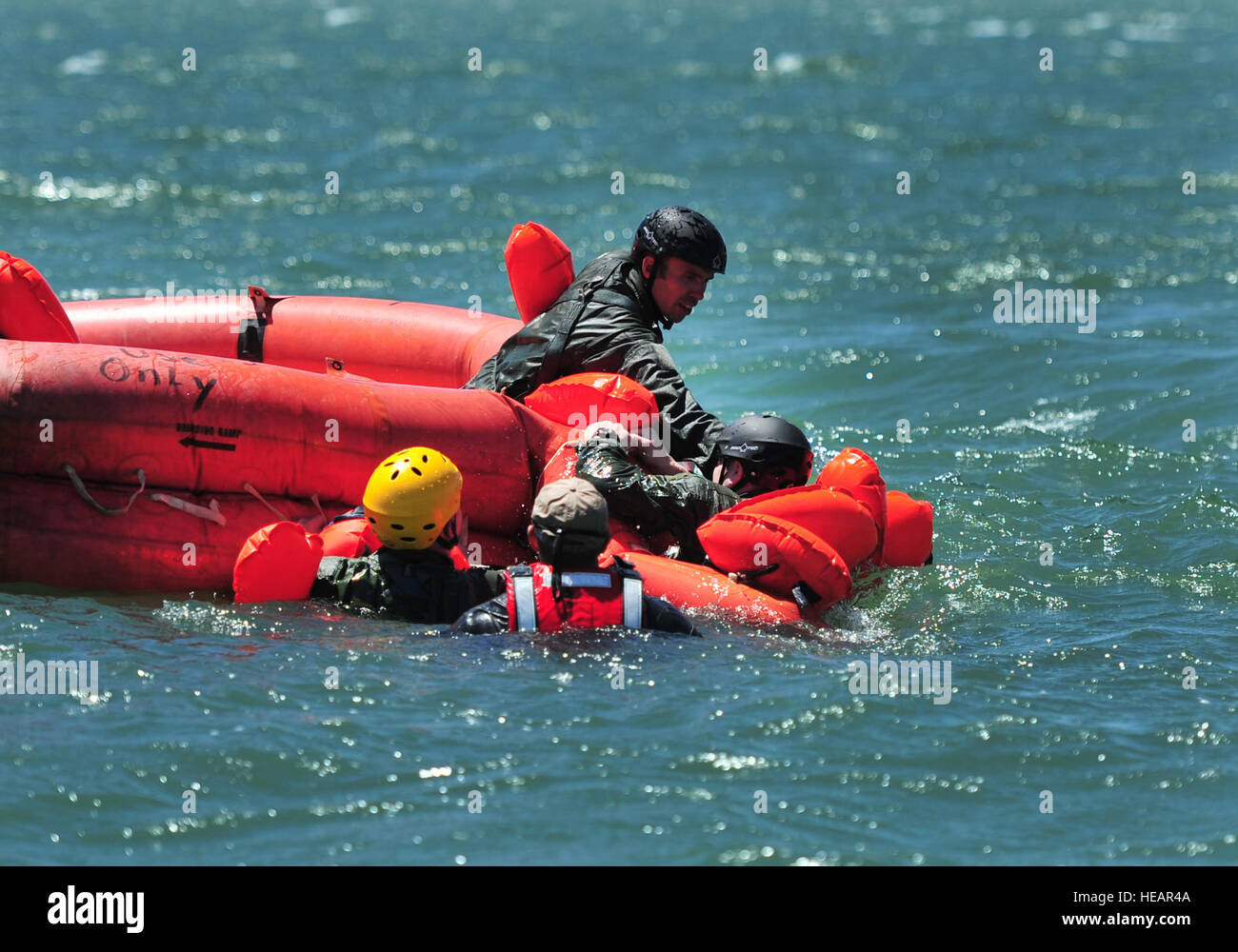 U.S. Air Force aircrew members help each other board a large life raft ...