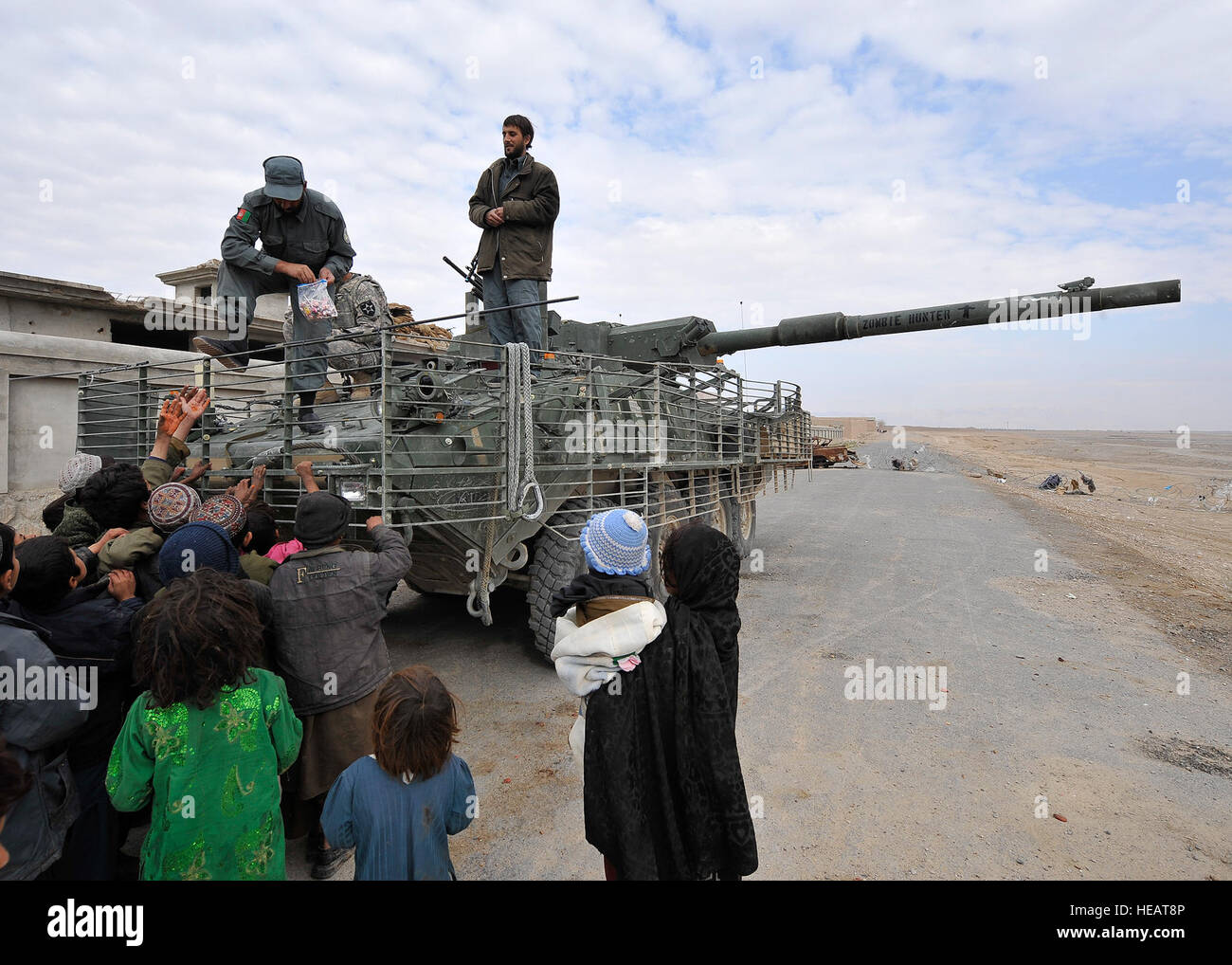 Afghan national policemen pass out candy while standing on a M1128 ...