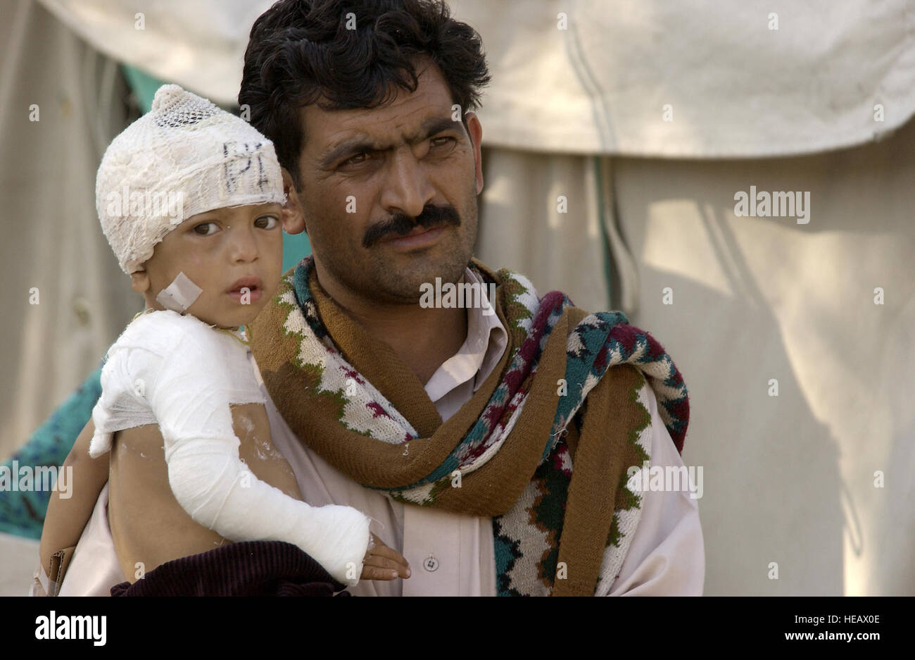 A Pakistani father holds his son outside a makeshift field hospital in ...