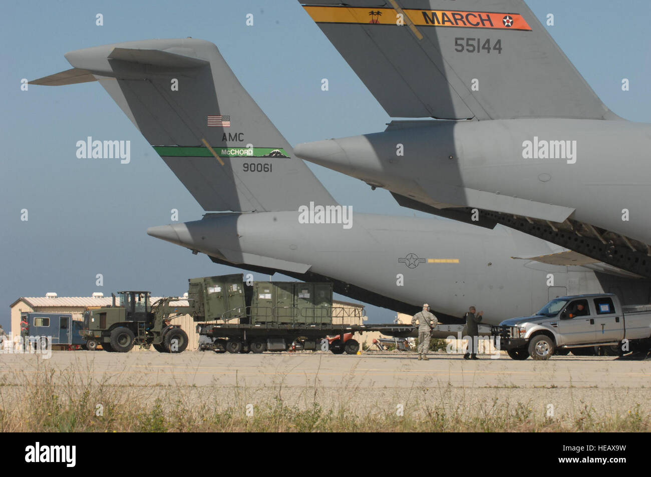 U.S. Air Force airmen load cargo onto two C-17 Globemaster III aircraft ...