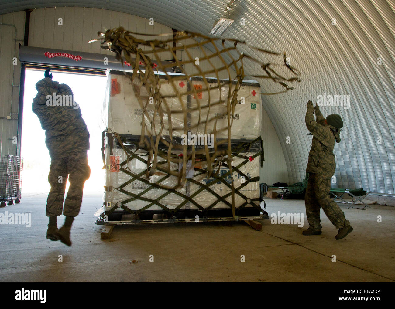 U.S. Air Force airmen toss a pallet net over cargo so they can secure ...