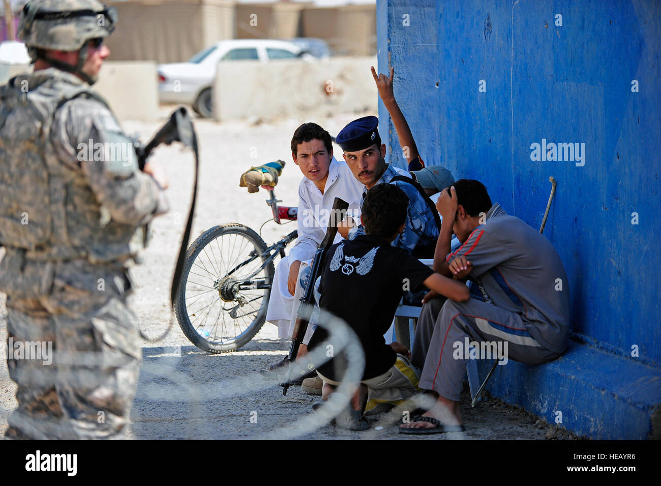 An Iraqi police officer sits with local children along a wall after U.S ...