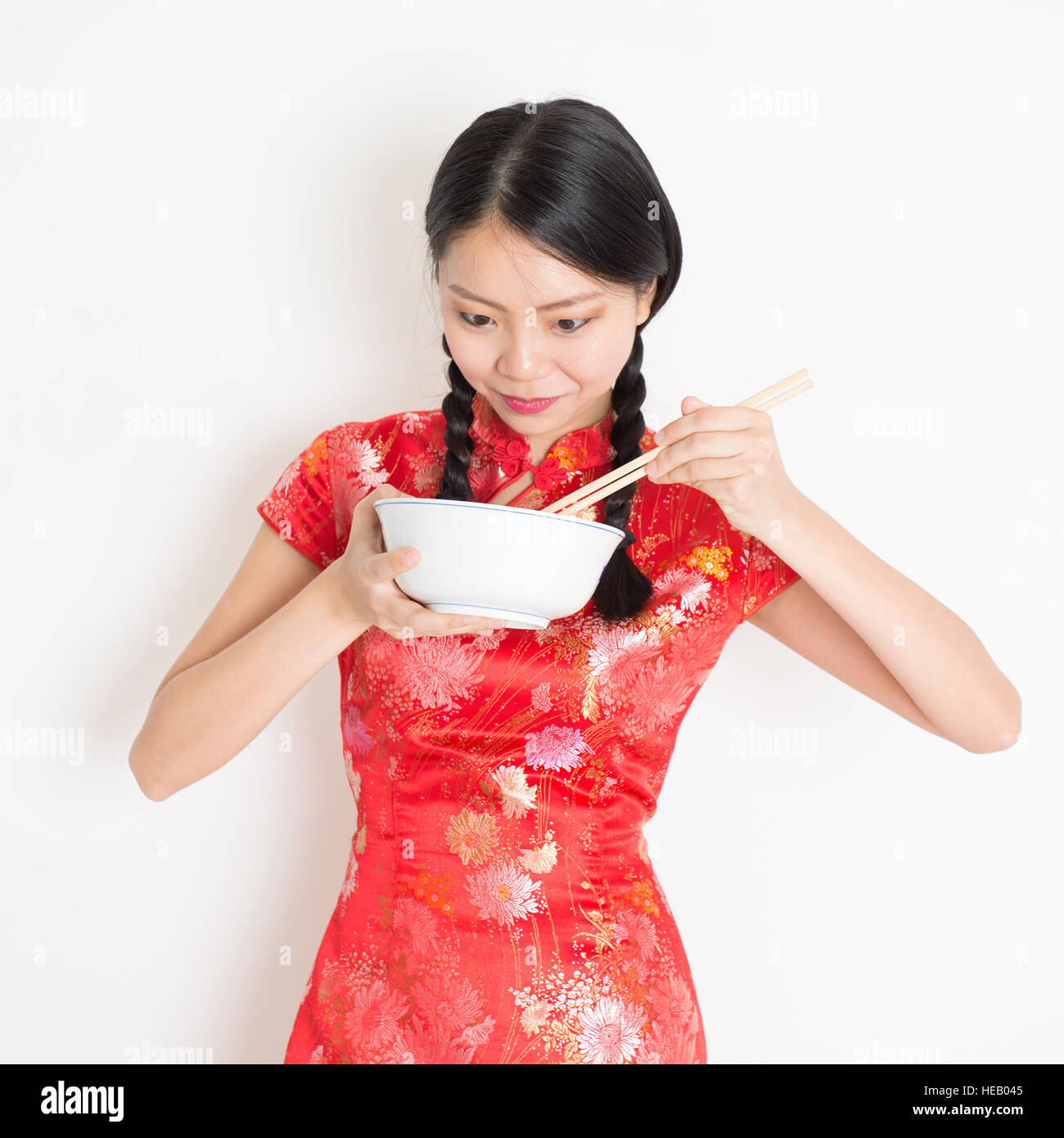 Portrait of young Asian female in traditional qipao dress eating, hand ...