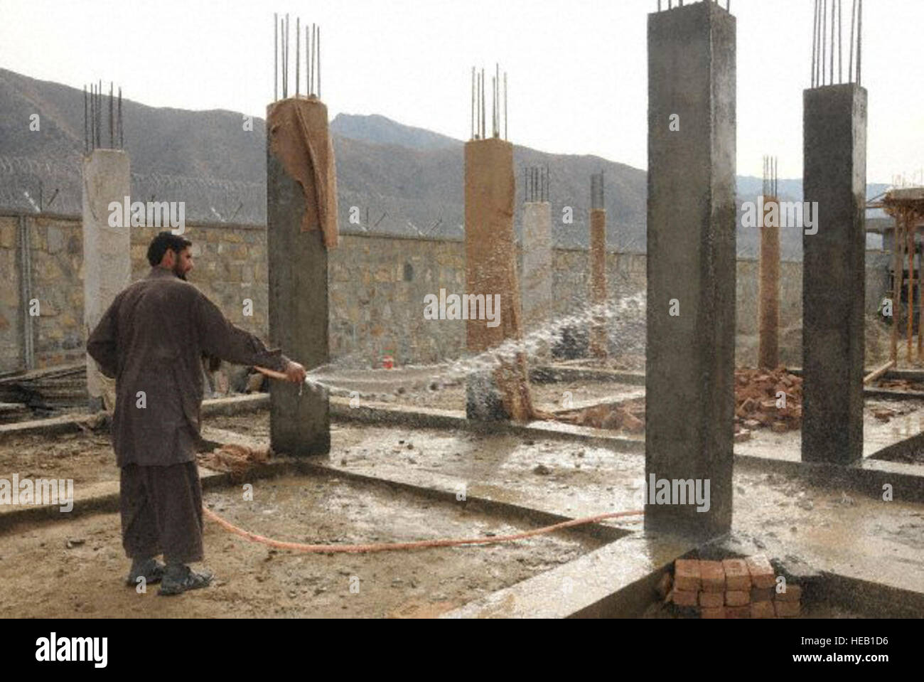 A construction worker moistens the concrete work at the Kunar Prison ...