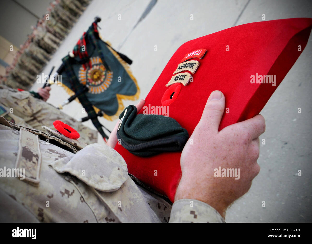 A Canadian service member holds a pillow bearing the badges, beret and ...