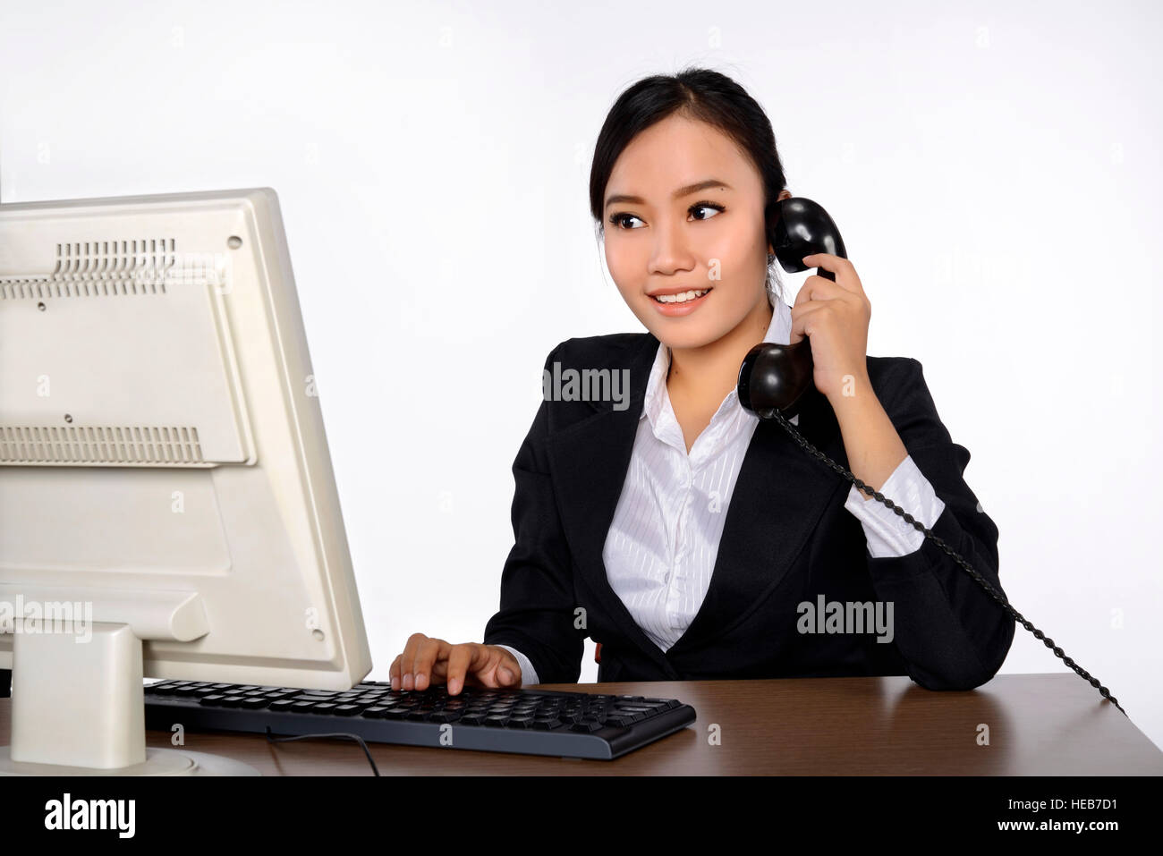 Attractive young business woman sitting, using computer, talking on the ...