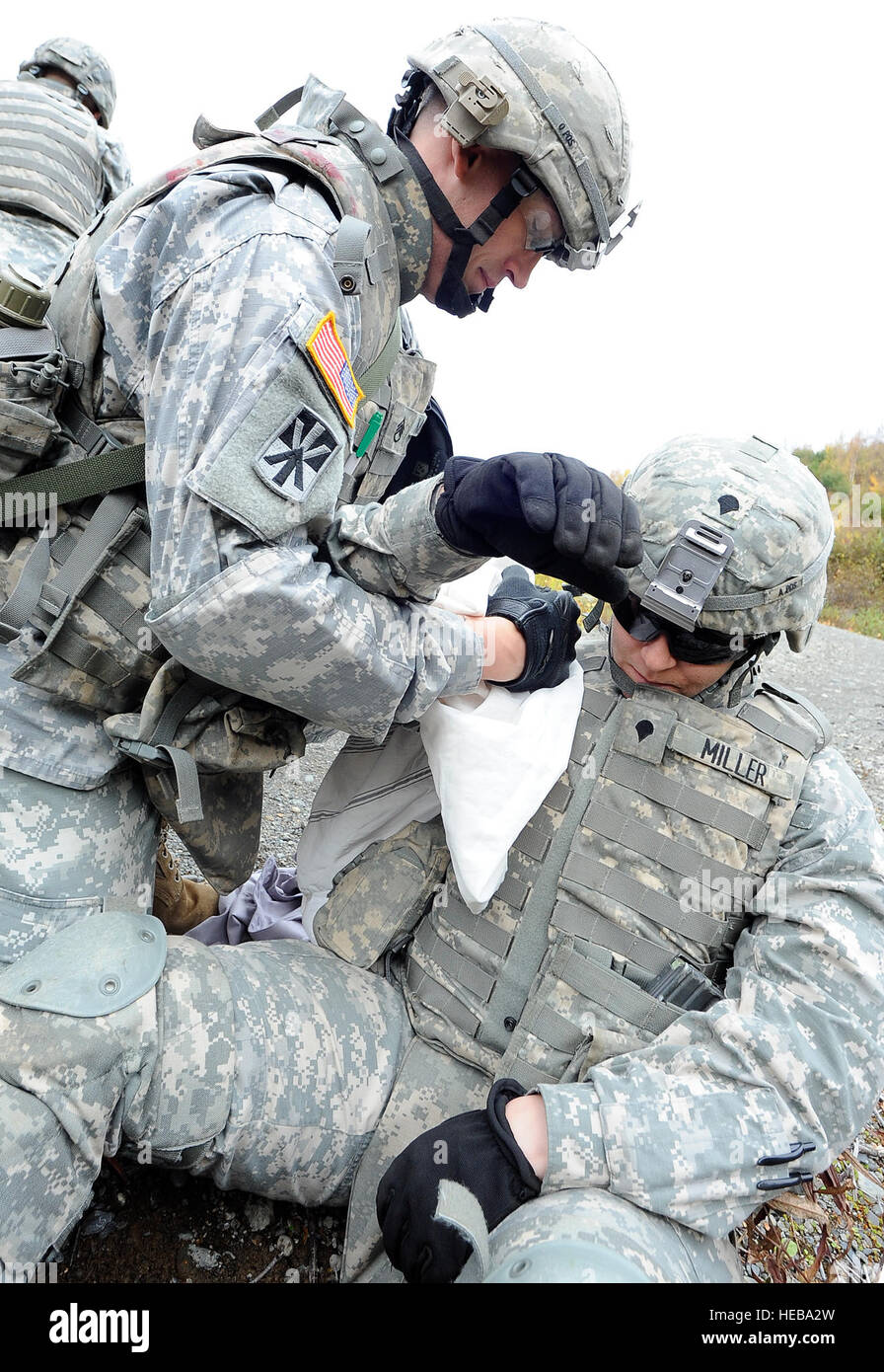 Staff Sgt. Jason Moore (l), applies an improvised field dressing to Spc ...