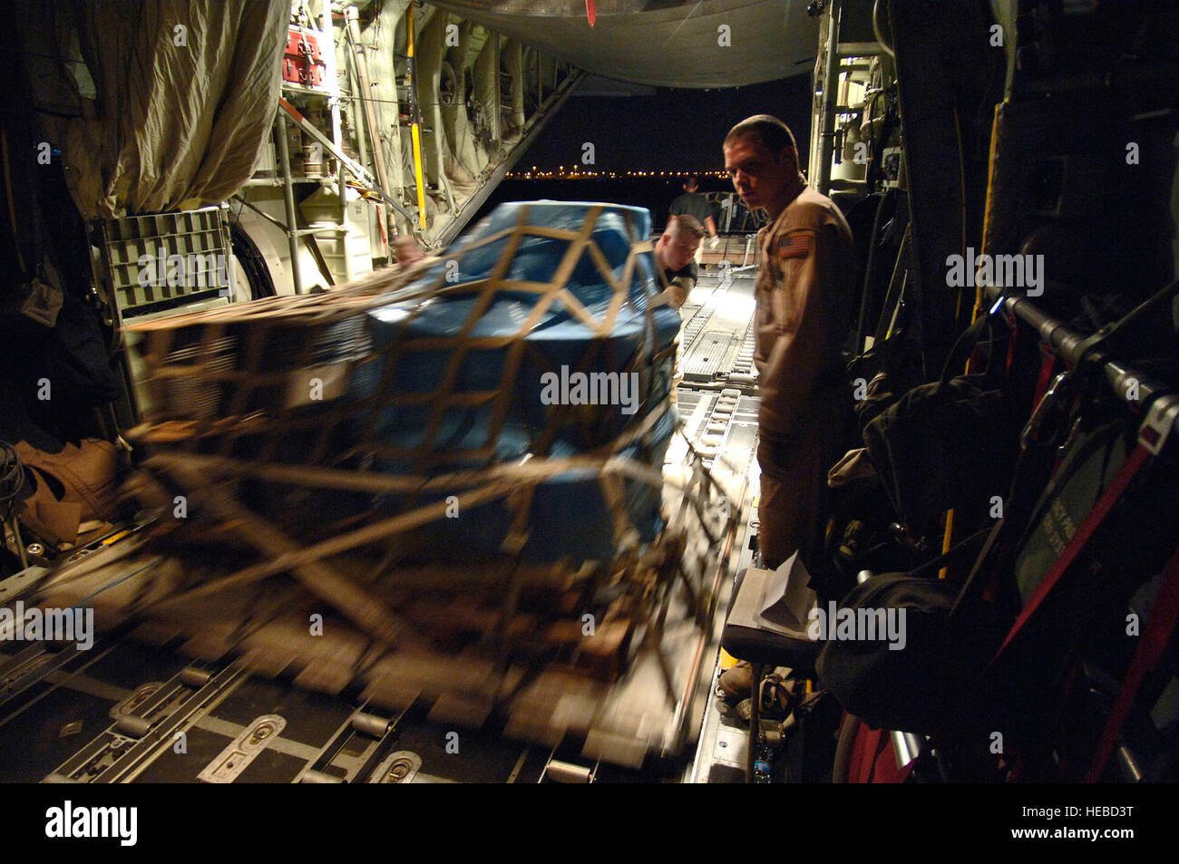 Senior Airman Robert Fisher pushes a cargo pallet into place while ...