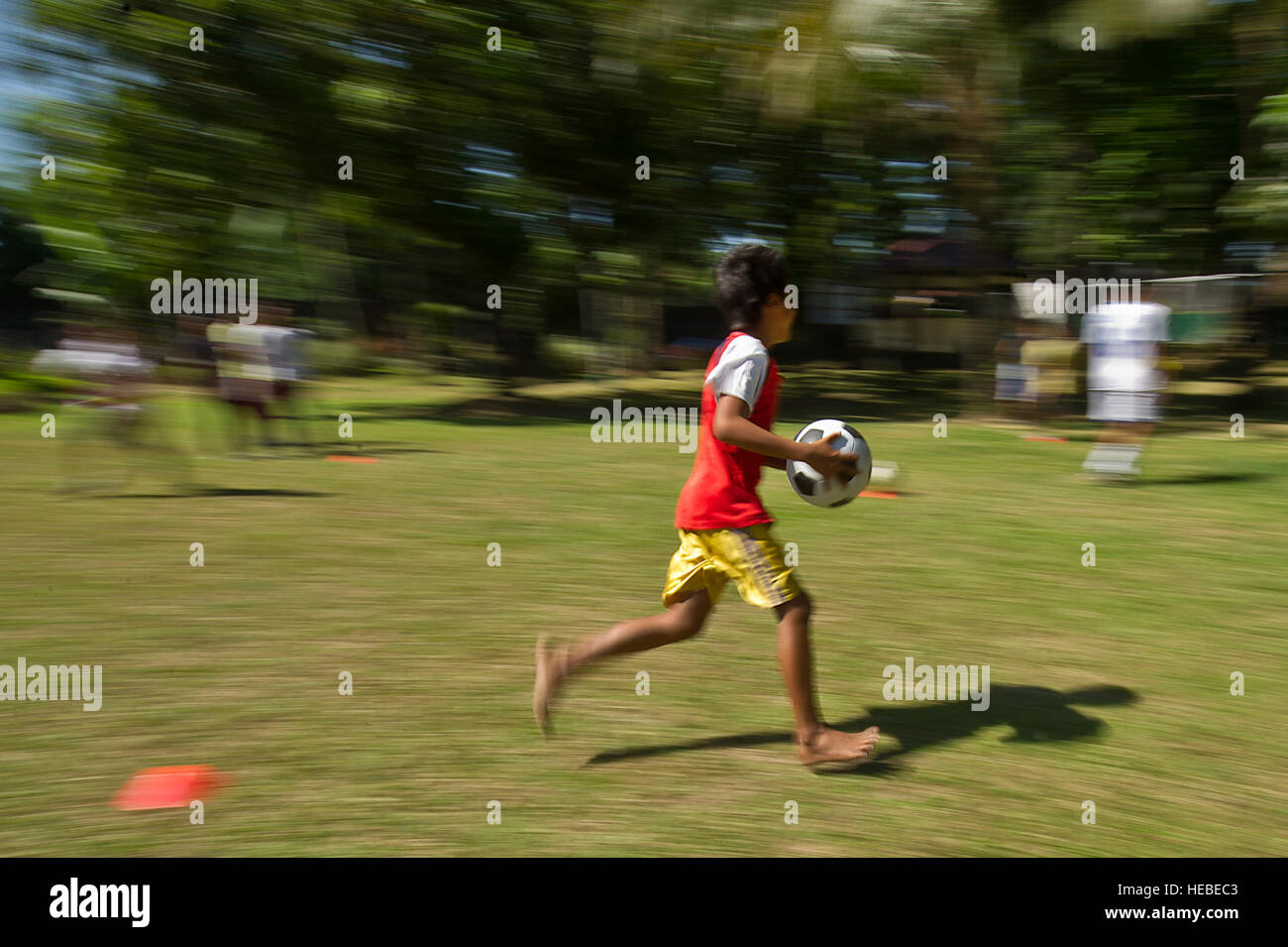 A Filipino boy runs with a football during a youth futbol clinic for ...