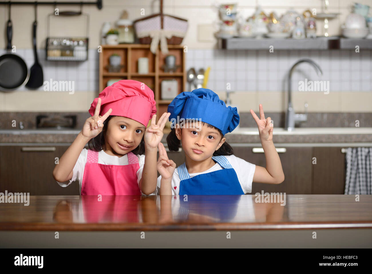 Two little chef show victory sign in the kitchen Stock Photo - Alamy