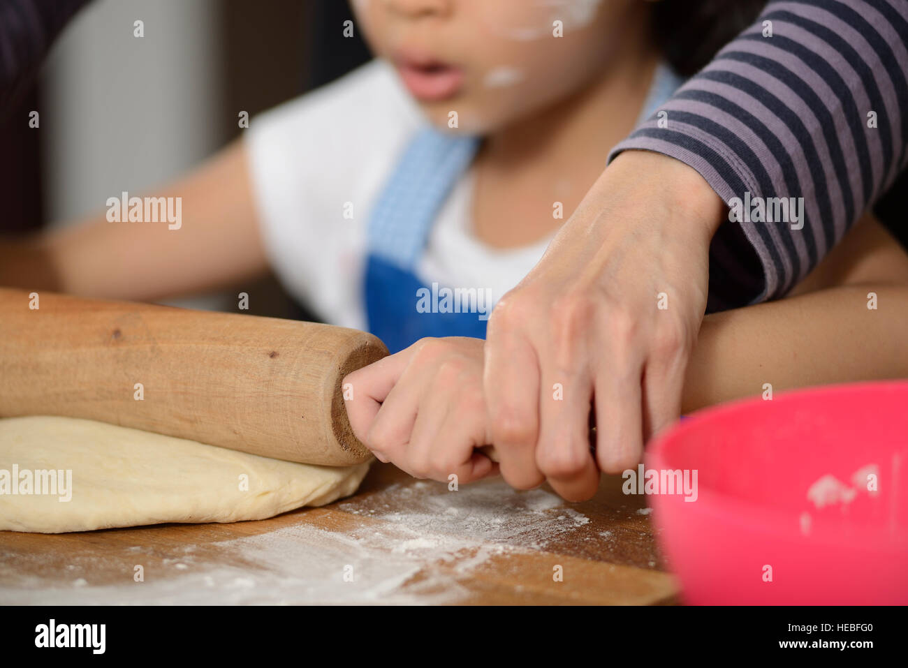 Mother teaching her daughter making bread with rolling pin on the ...