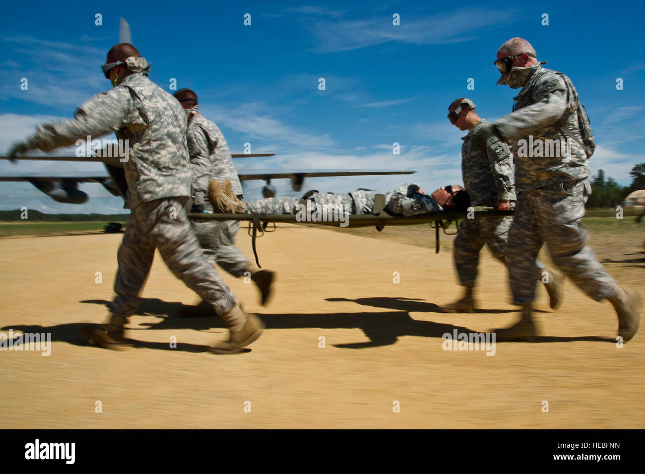 U.S. soldiers carry an injured comrade using a litter on to a C-130 ...